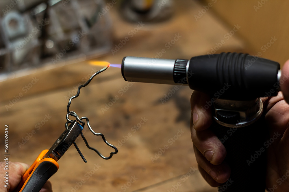 Old man working, using torch gun in his workshop, heating up some metal ...