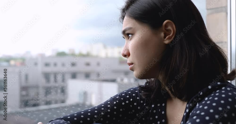 Video Stock Close up view face sad Asian woman sit on windowsill look ...