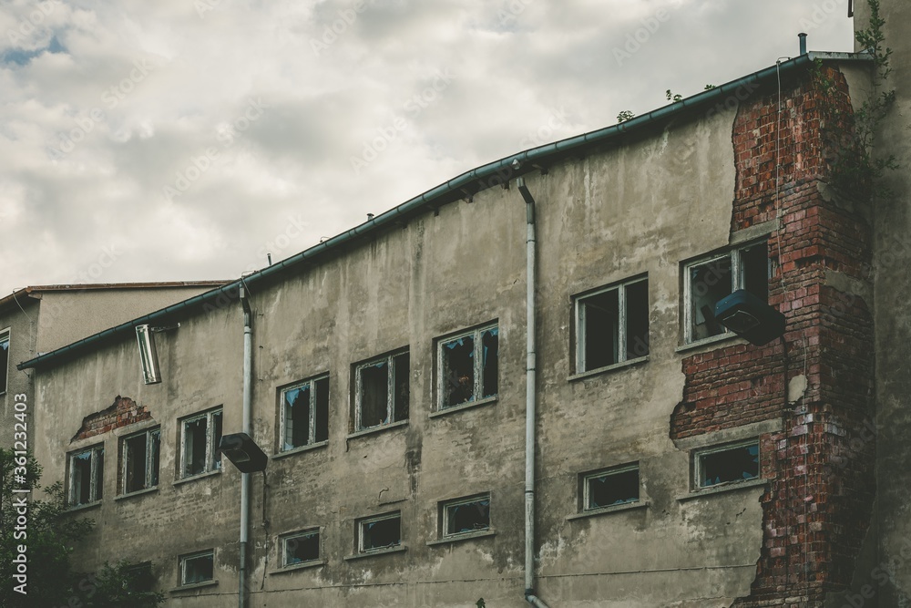 Old worn down building with grey walls and bricks sticking out on one ...