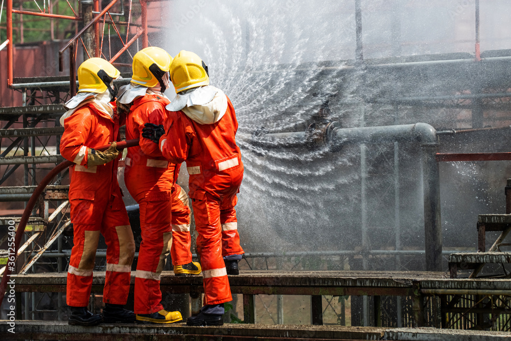 Foto de Group of firefighter in fire suit on rescue duty using water ...