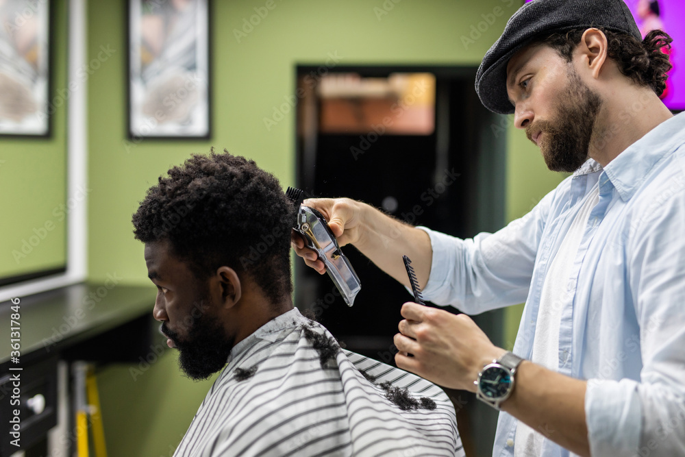 Closeup of process of trimming of hair in barber shop. Qualified barber ...