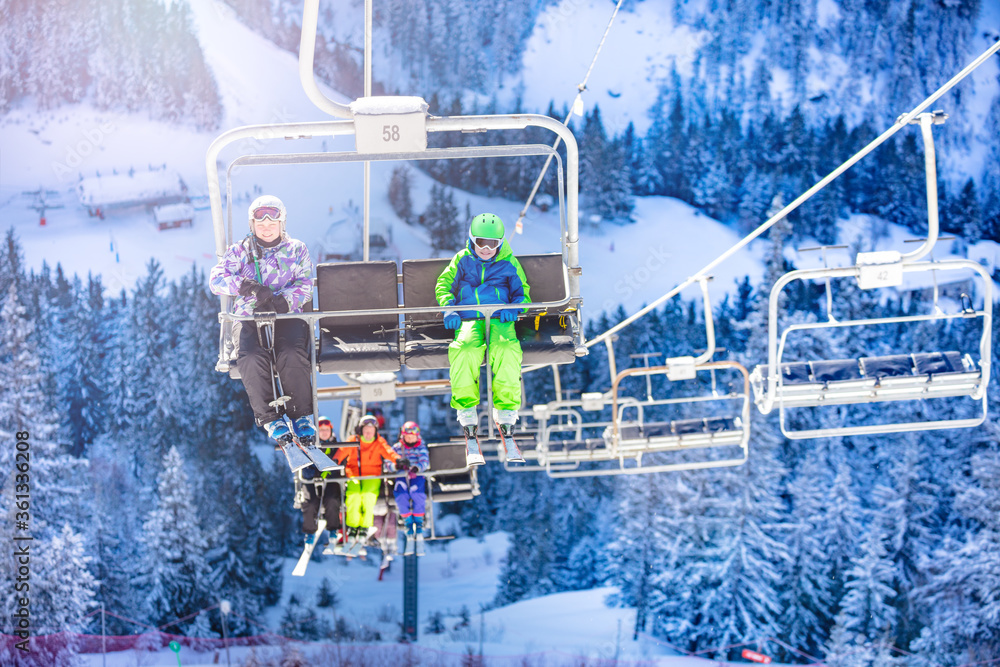 Boy and girl sit on chairlift with friends going on second chair all ...