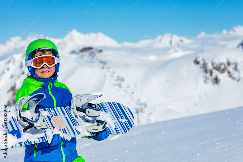 Cute little boy hold snowboard with mountain snow winter resort and ski ...