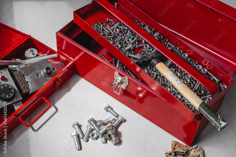 two open red tool boxes on concrete, inside a hammer, nuts and bolts ...