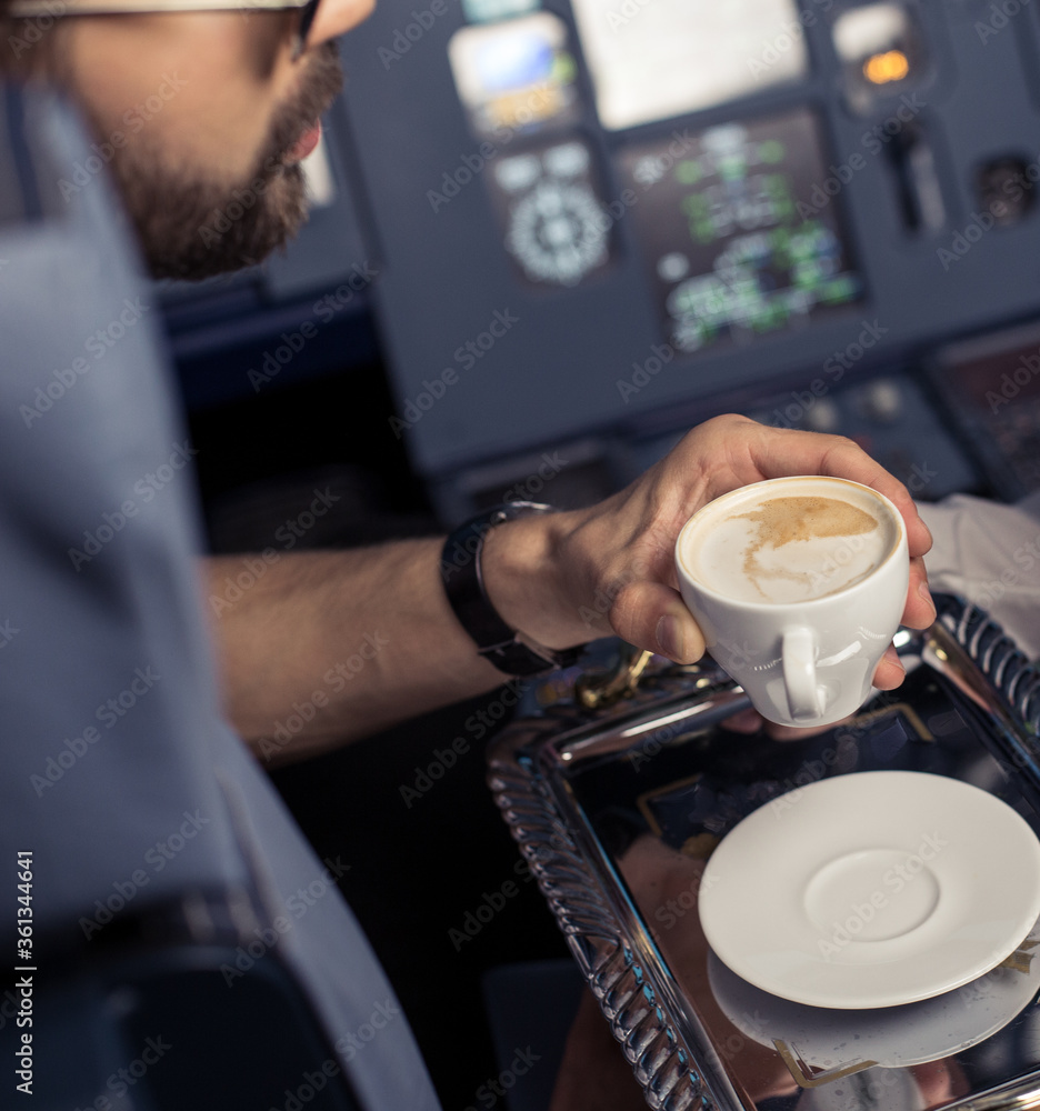 Coffee time during the flight. Young pilot in the aircraft in front of ...