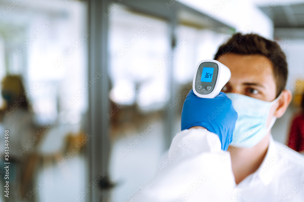 Hand in glove holding ir thermometer. Medical office measurement ...