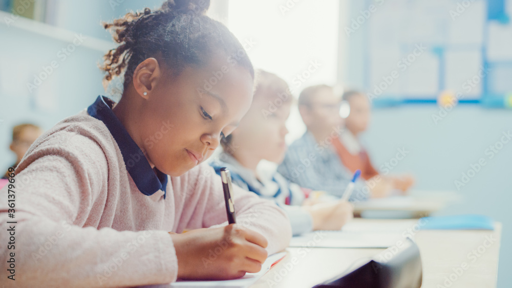 In Elementary School Classroom Black Girl Writes in Exercise Notebook ...