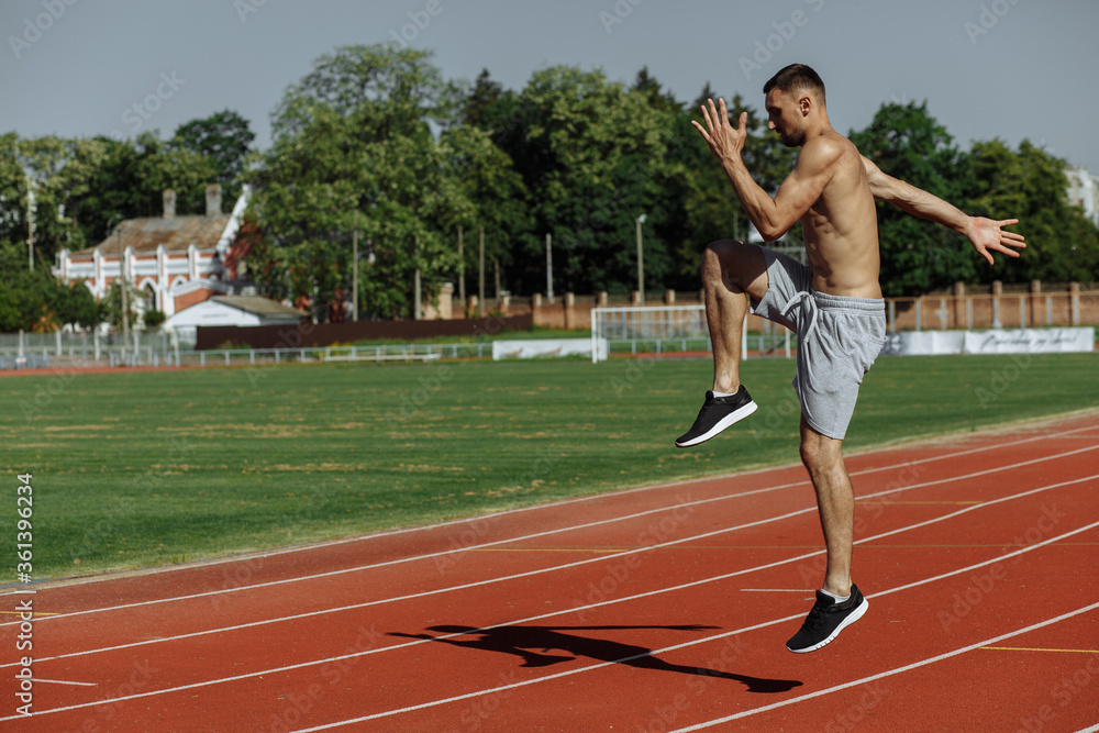 Shirtless muscular man jumping up at the stadium. Sportsman. Strong man ...