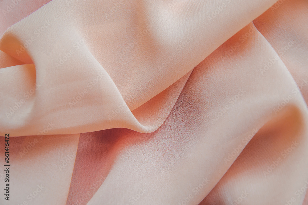 Close up picture of silk fabric with wavy holds in peachy pink color ...