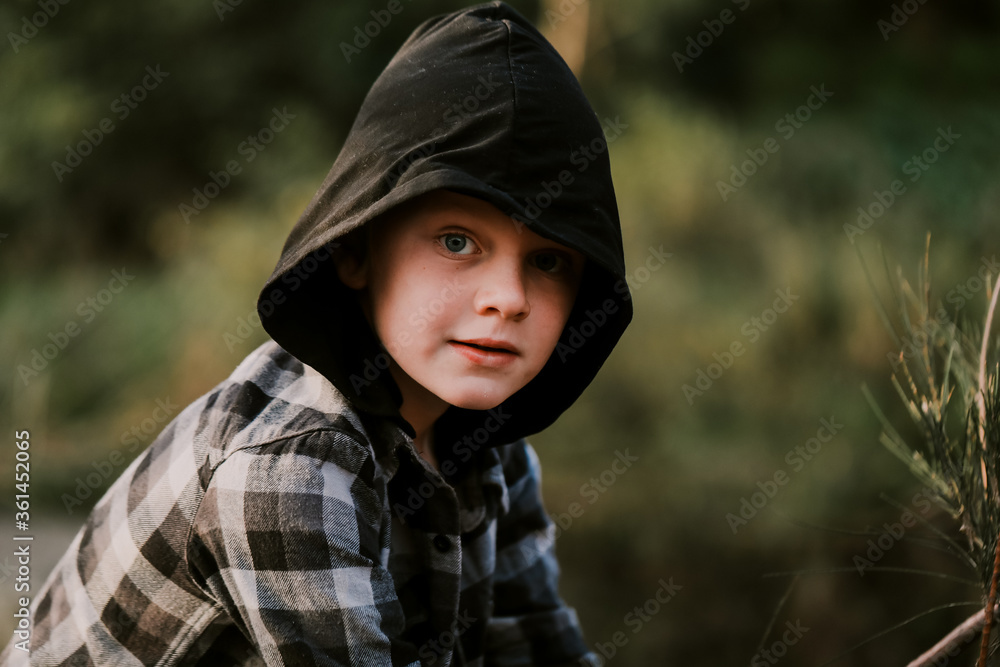 Dark and moody image of little boy exploring in nature wearing hoodie ...