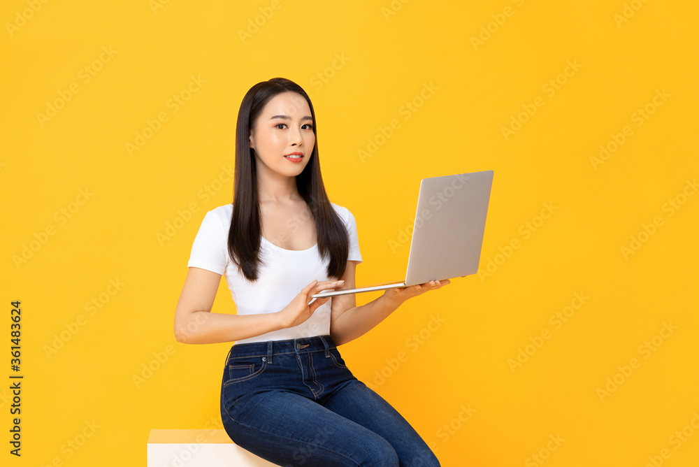 Portrait of happy attractive young Asian woman sitting and working with ...