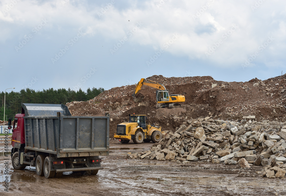 Excavator, dump truck and wheel loader at landfill for disposal of ...