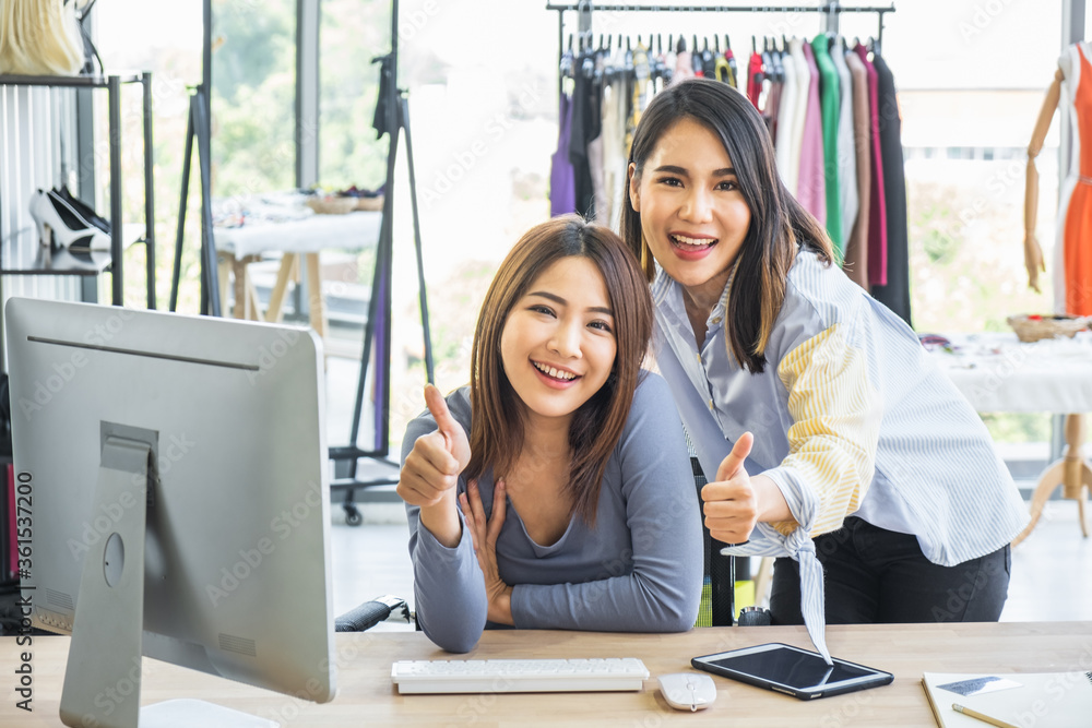 Two young Asian girls shop owners at work desk in front of a computer ...