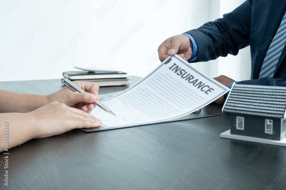 A real estate agent with a home model is talking to clients about ...