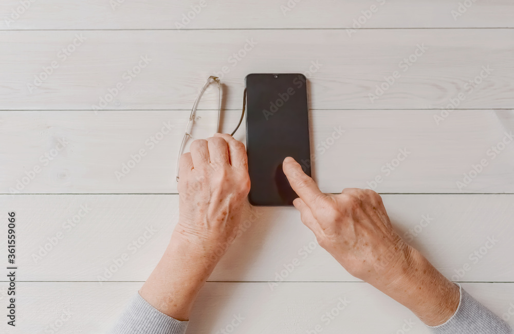 Old wrinkled hands holding mobile smart phone. Elderly woman using ...
