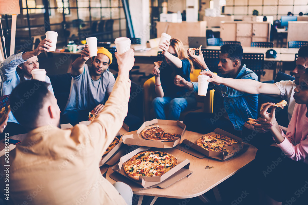Crew of employees celebrating successful startup raising cups with ...