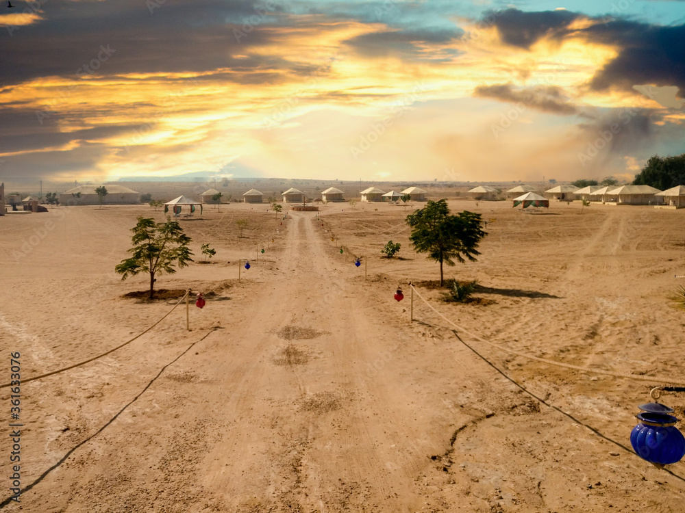 Empty dirt road with barren desert on both sides and blue sky above ...