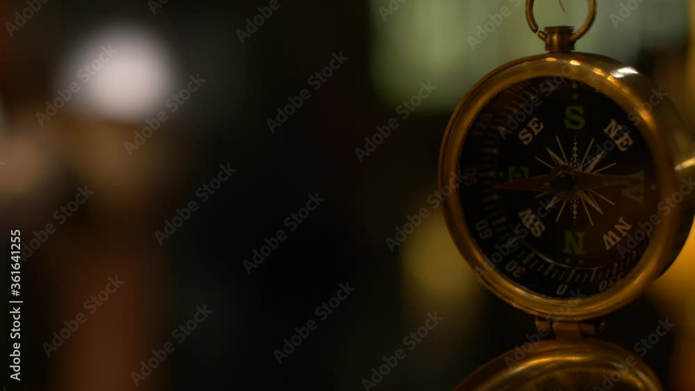 ornate brass compass hanging in front of background of blurred people ...