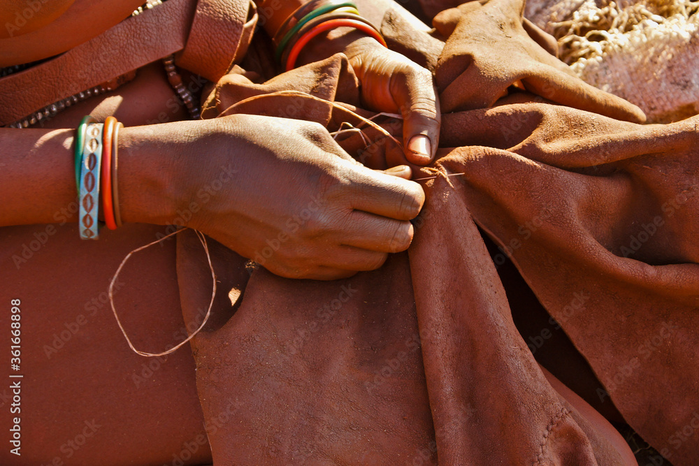 Hands of Himba woman sewing leather in a tribal village near Opuwo ...