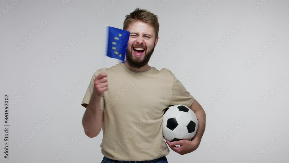 Joyful happy football fan bearded guy in t-shirt holding soccer ball ...