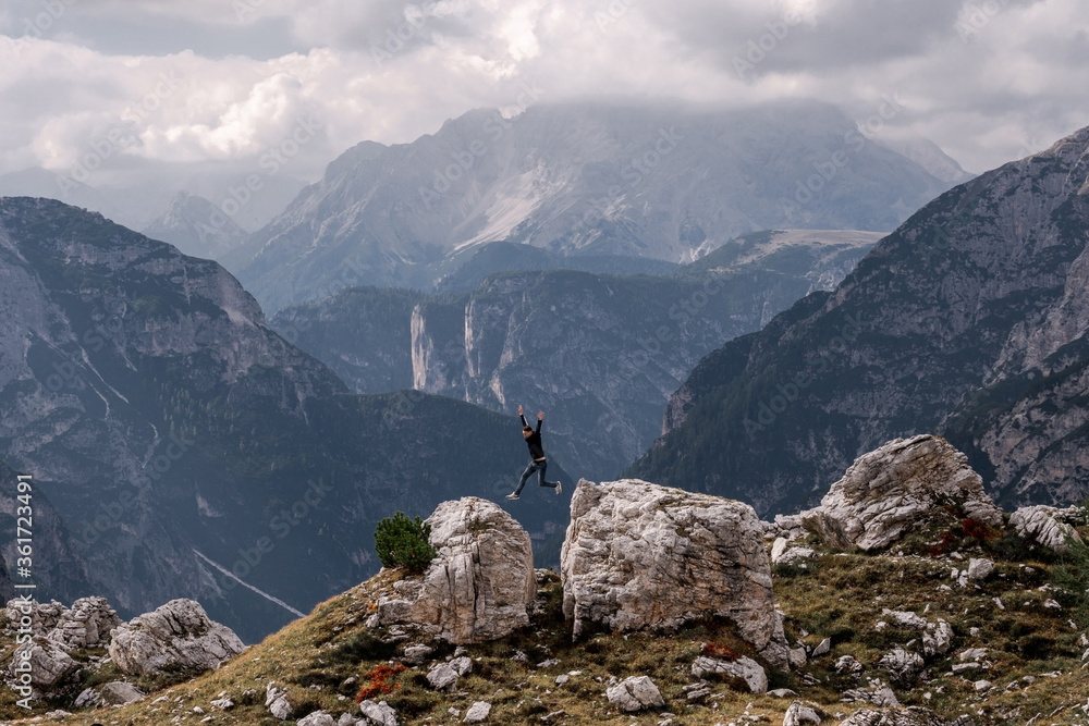 Dolomites Alps. Italy. Young hiker man jumps from the stone over the ...