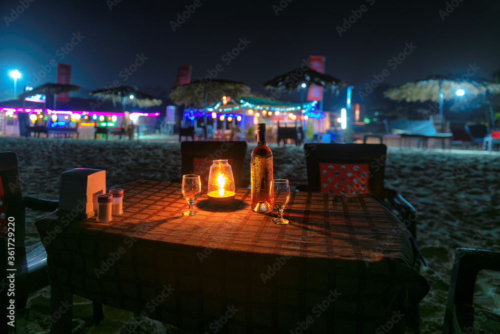 Beach party at night in beach cafe with bottle of rose wine and glasses ...