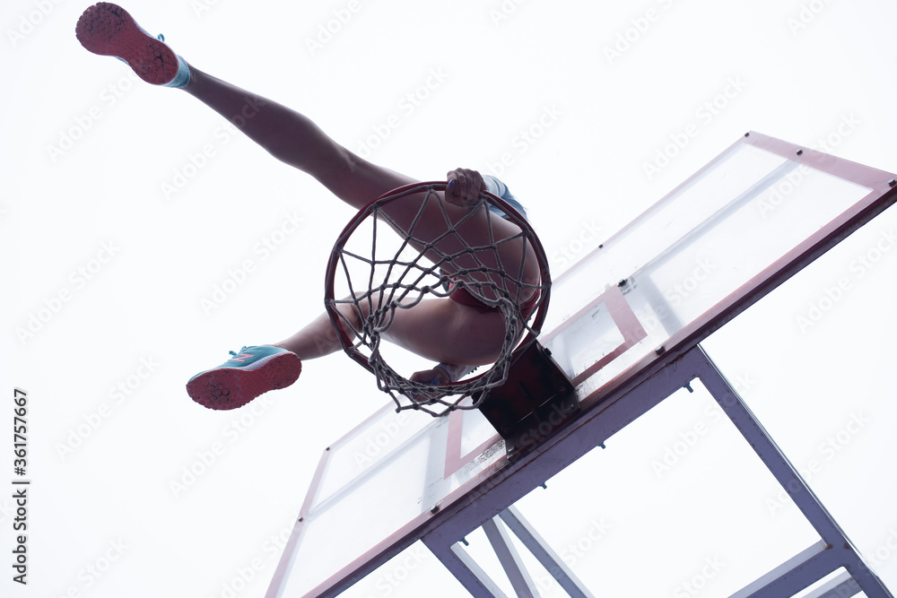 Young girl sitting on a basketball hoop Stock Photo | Adobe Stock