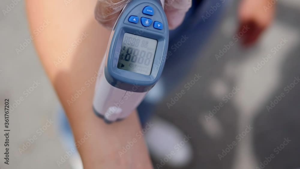 A nurse measures a patient’s temperature using a non-contact infrared ...