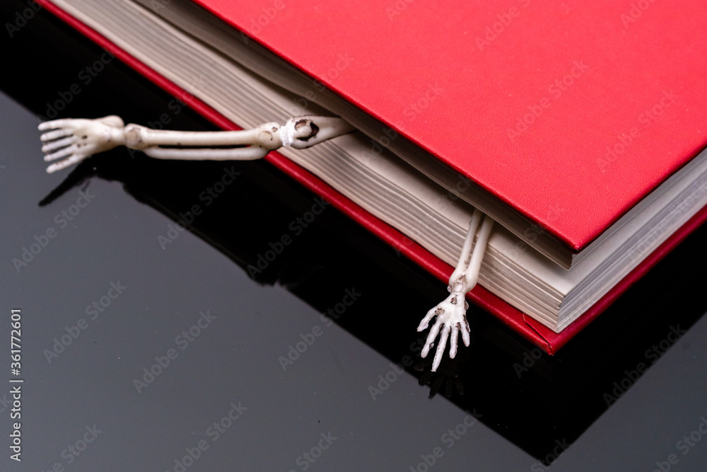 parts of the human skeleton crawling out of a closed red book. horrible ...