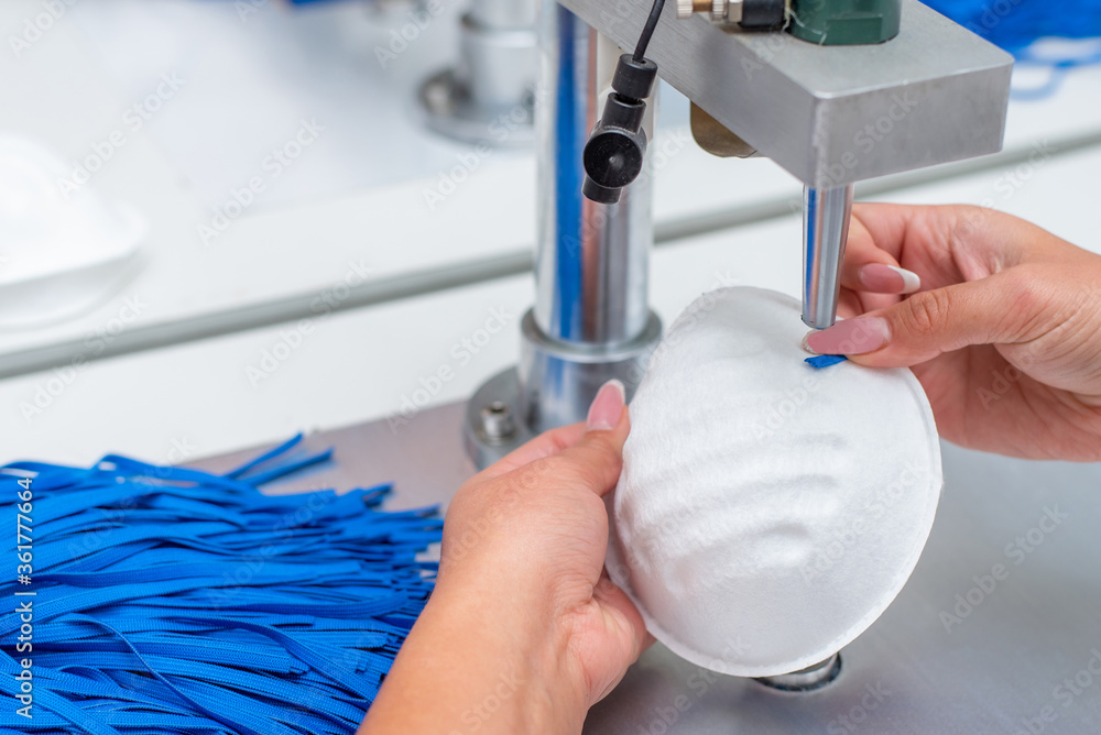 The girl works in a factory for the production of medical masks with ...