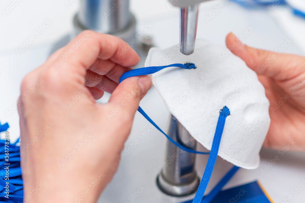 The girl works in a factory for the production of medical masks with ...