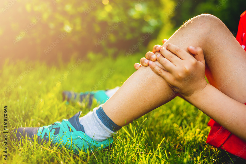 The child is holding his knees. The boy dressed in sports attire is ...