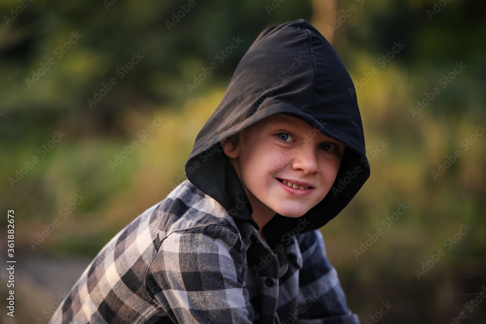 Dark and moody image of cute little boy wearing hoodie in naural ...