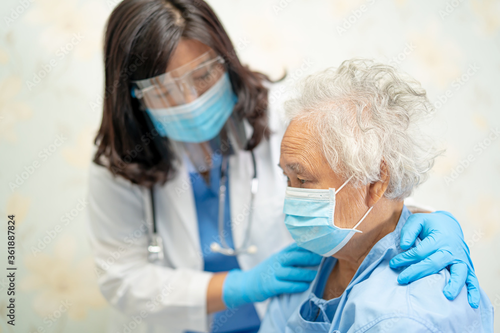 Asian doctor wearing face shield and PPE suit to check patient protect ...