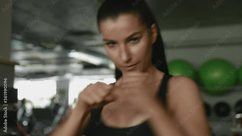 Confident strong girl with dark hair in sport crop top boxing ...