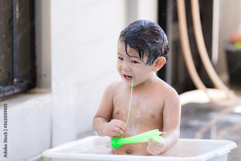 Portrait Asian baby boy playing water in white basin. Child washing ...