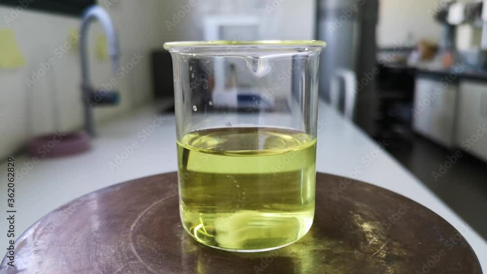 Lab technician using a magnetic stirrer to stir yellow solution ...