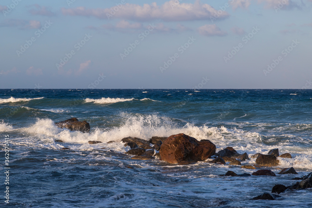 Beautiful black beach with coast and sea in Vlichada with blue sky ...