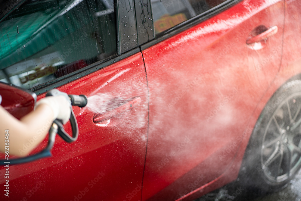 Cheerful beautiful Asian woman washing her modern red car by using a ...