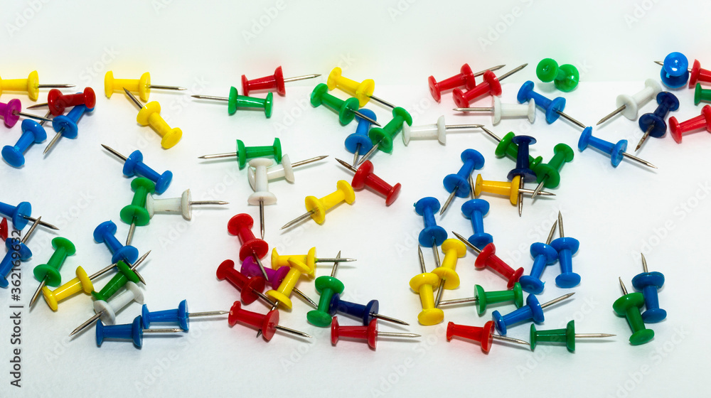 Sharp pin for attaching paper. Colored stationery buttons laid out on ...