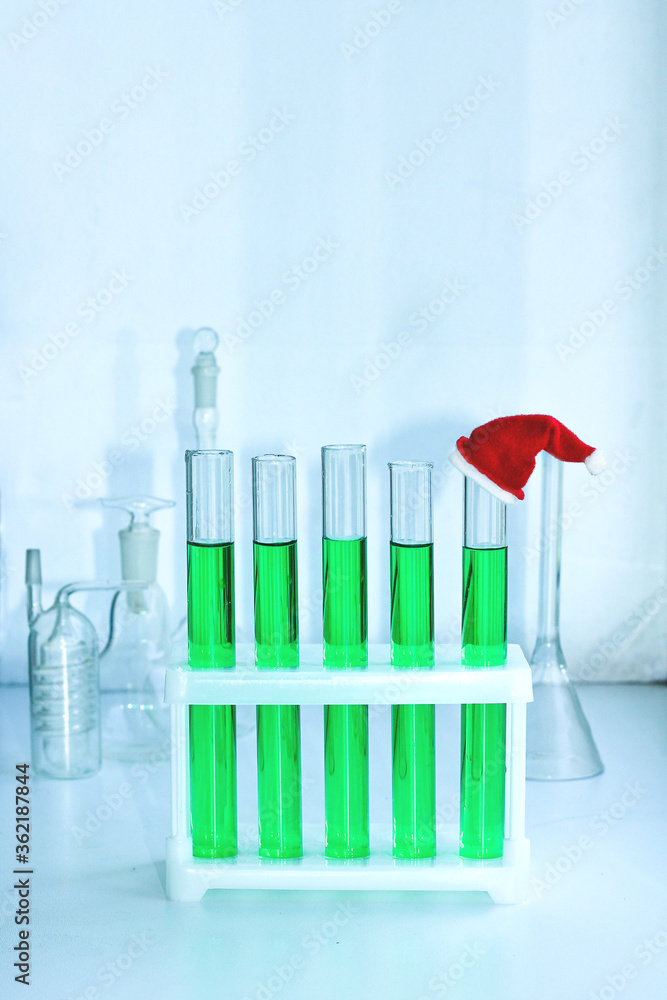 five vials of green solution in a chemical lab. on the end tube is a ...