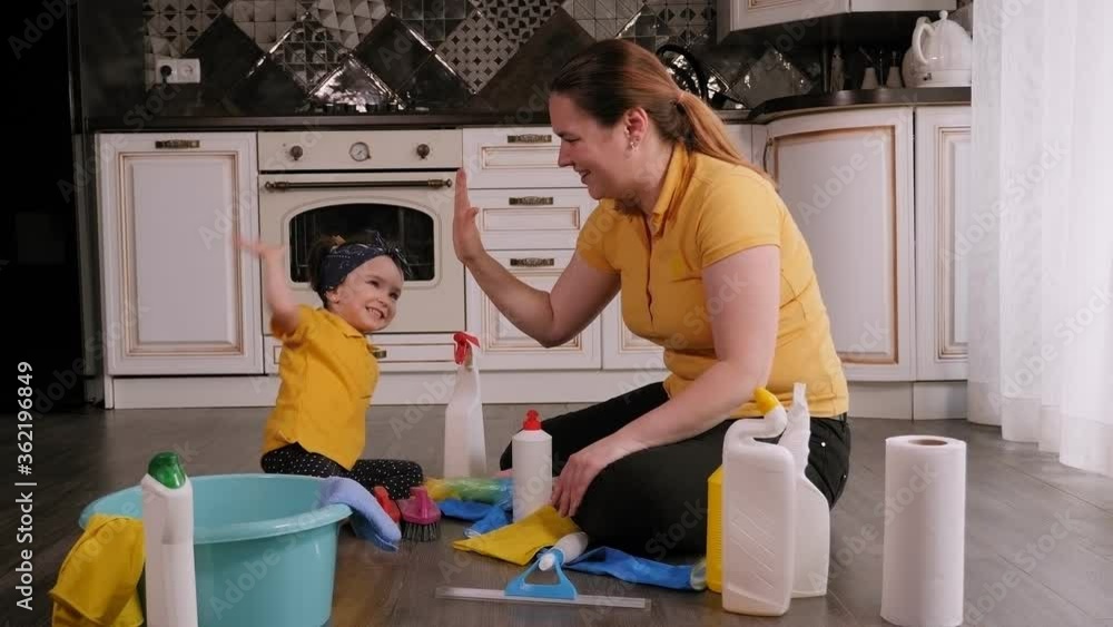 A happy mother and her little daughter are cleaning the house together ...
