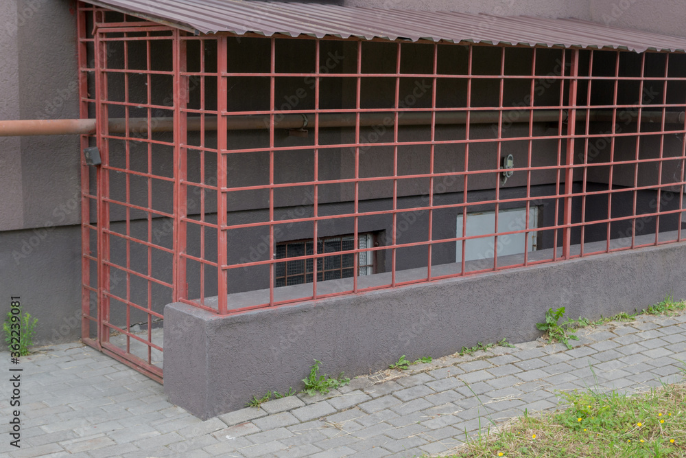 Cage with locked gate with black padlock, welded from red metal ...