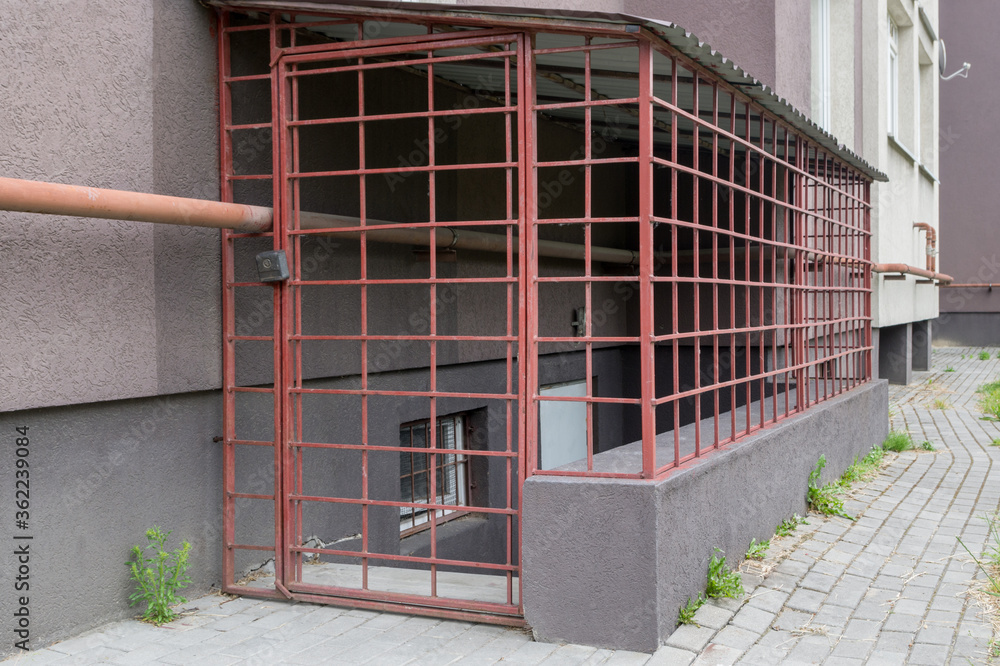 Cage with locked gate with black padlock, welded from red metal ...