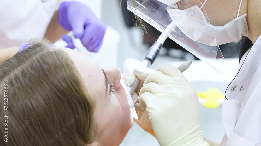 Closeup female dentist with patient at clinic. Drills the teeth of a ...