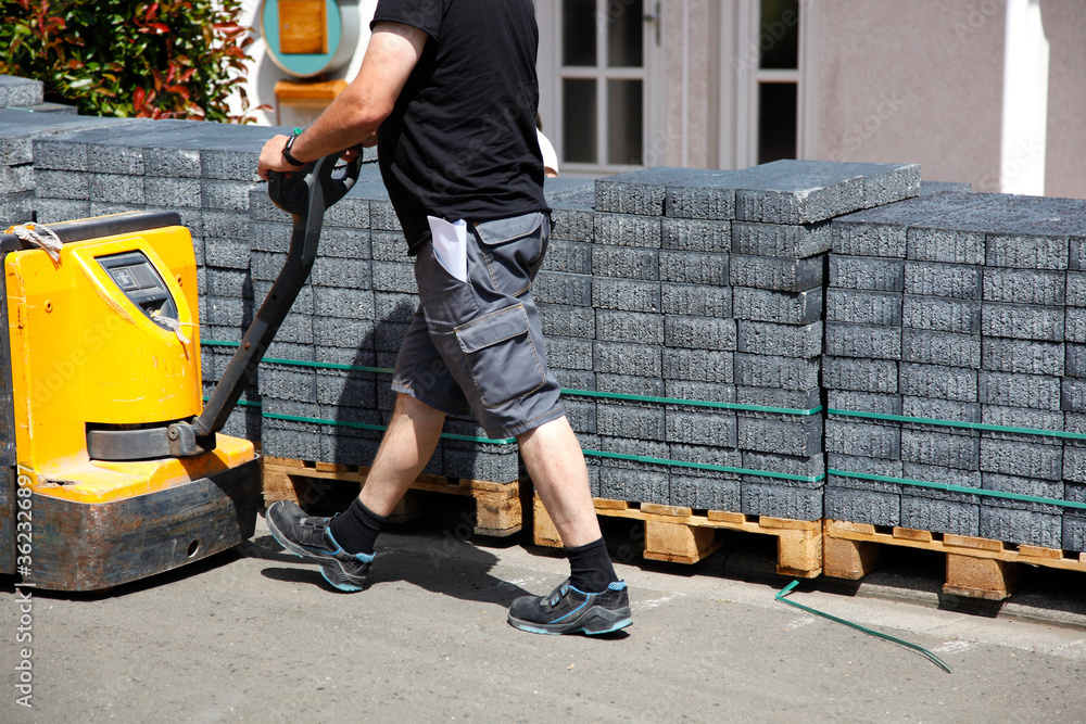 A fork pallet truck stacker with stack of concrete paving slabs ...