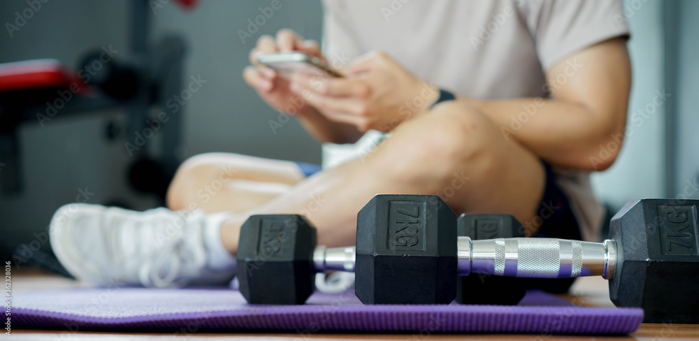 close up on dumbbell on the floor with man sitting and playing ...