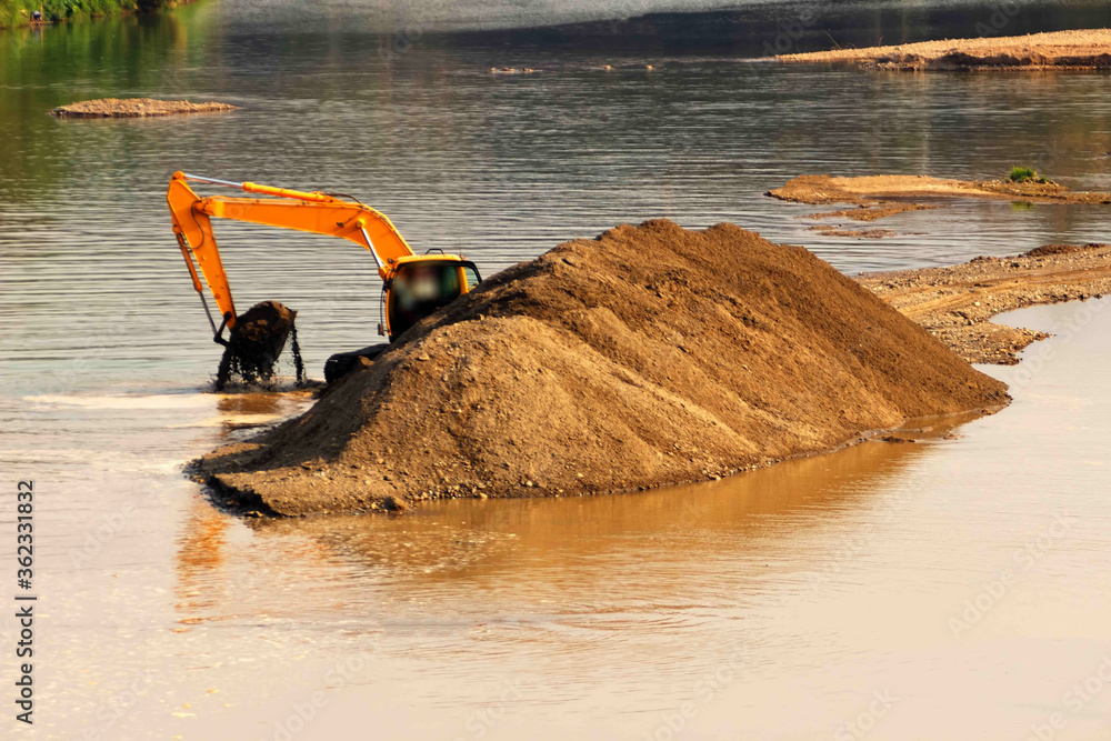 Excavator extracts sand and pebbles from a river in Southeast Asia ...