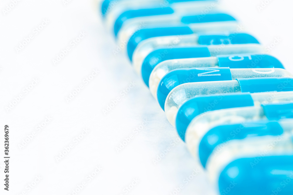 Blue gelatin capsules with white granules inside, isolated on a white ...