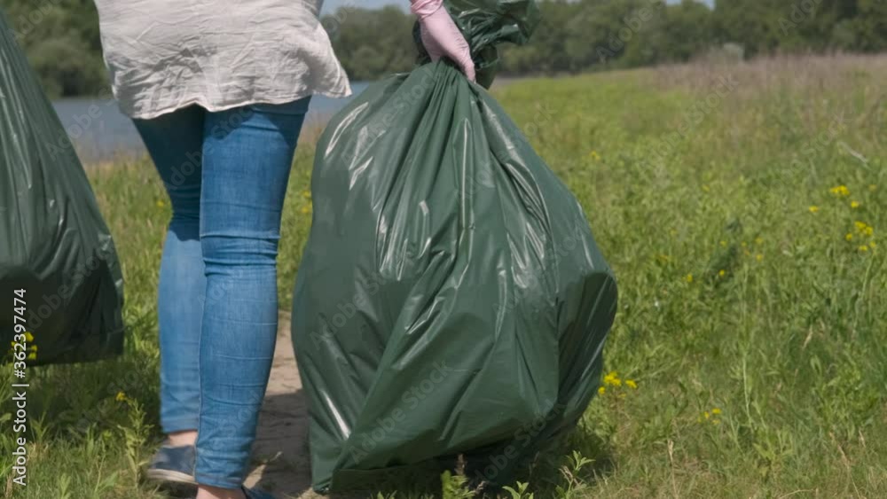 Woman with garbage bags. A woman with bags of plastic rubbish walks in ...